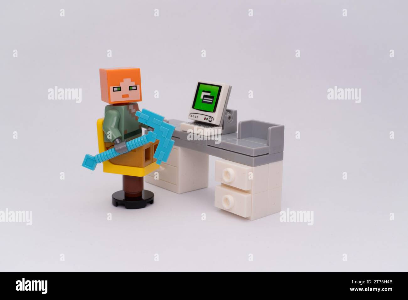 A small toy figurine seated at a desk made of blocks in front of a ...