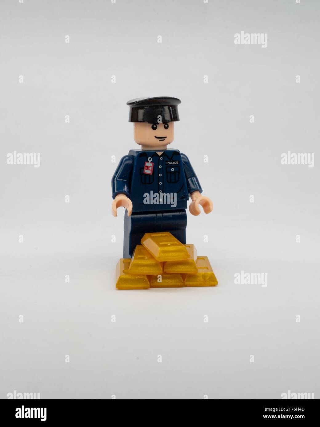 A police officer figurine standing in front of a stack of golden blocks ...