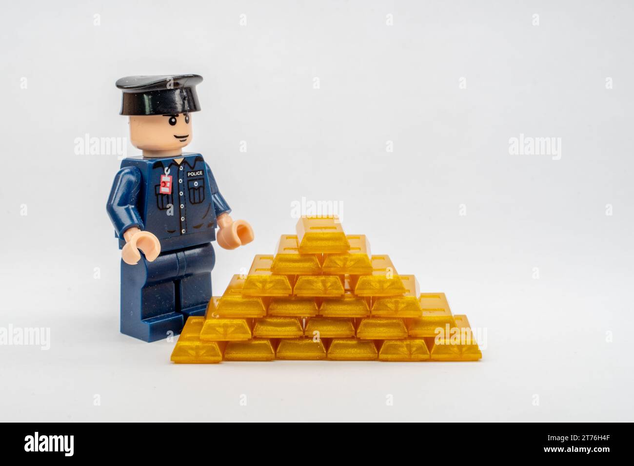 A police officer figurine standing in front of a stack of golden blocks ...