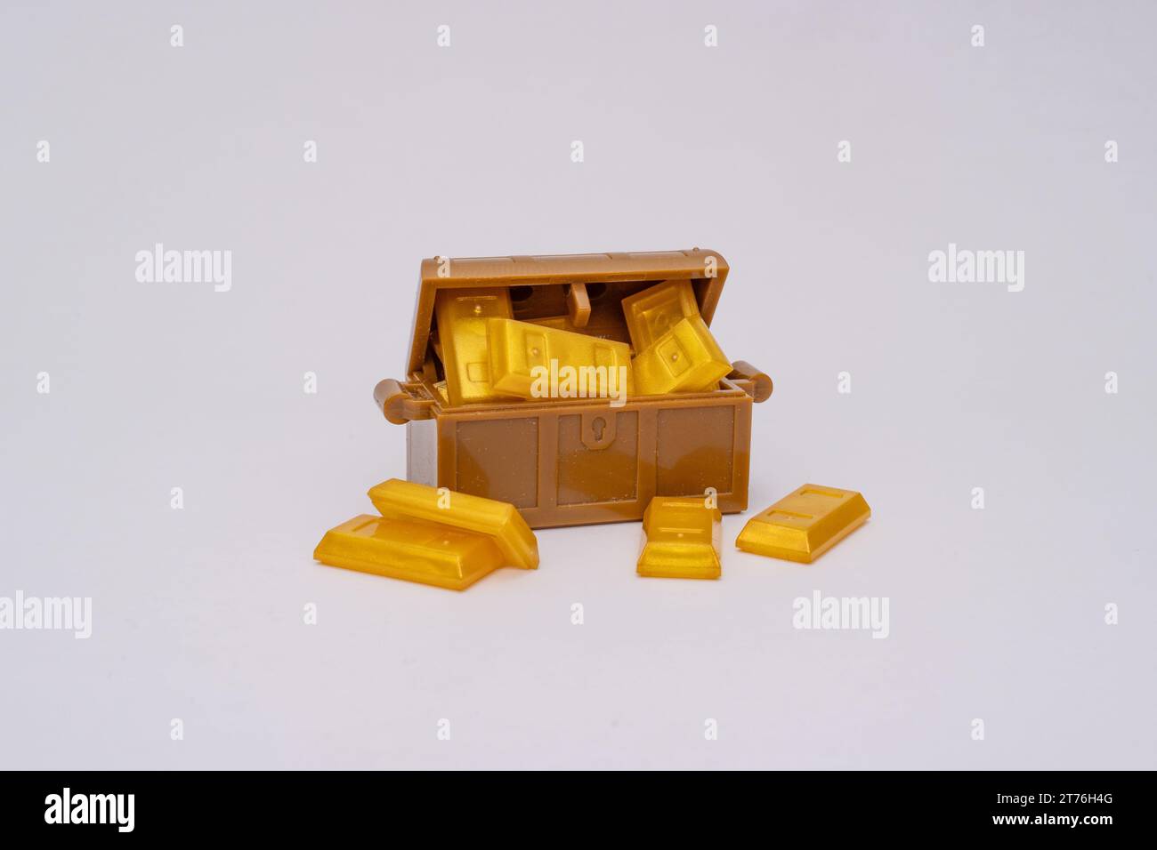 A miniature wooden chest toy with golden bars inside against a white ...