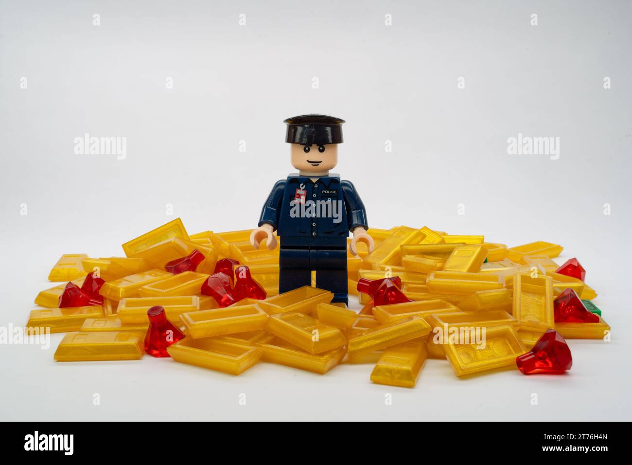 A police officer figurine standing in front of a stack of golden blocks ...