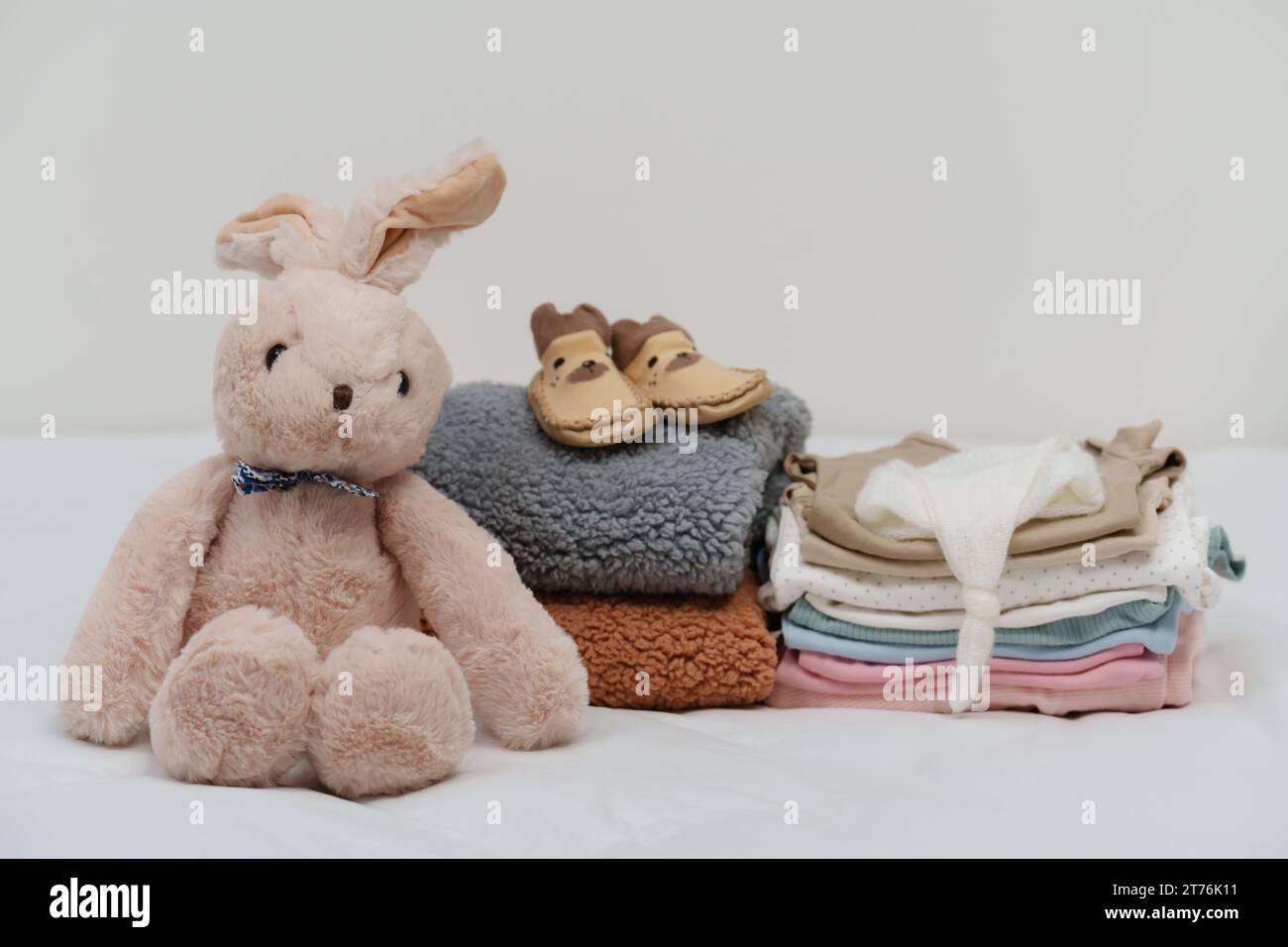 stack of baby clothes and shoes and toy on a bed Stock Photo - Alamy