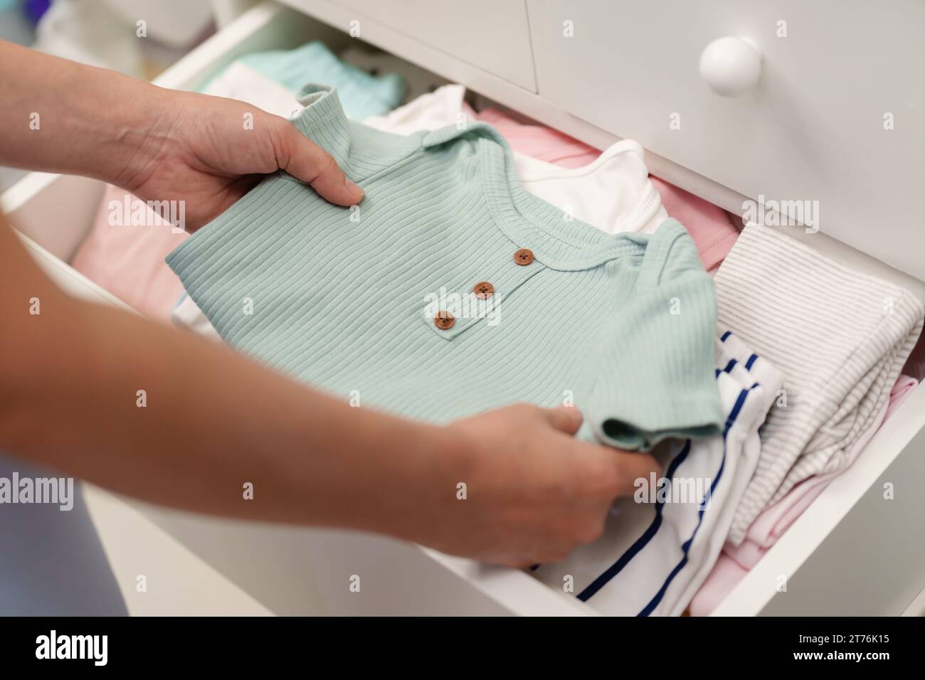 hand of mother taking baby clothes from open cabinet drawer Stock Photo ...
