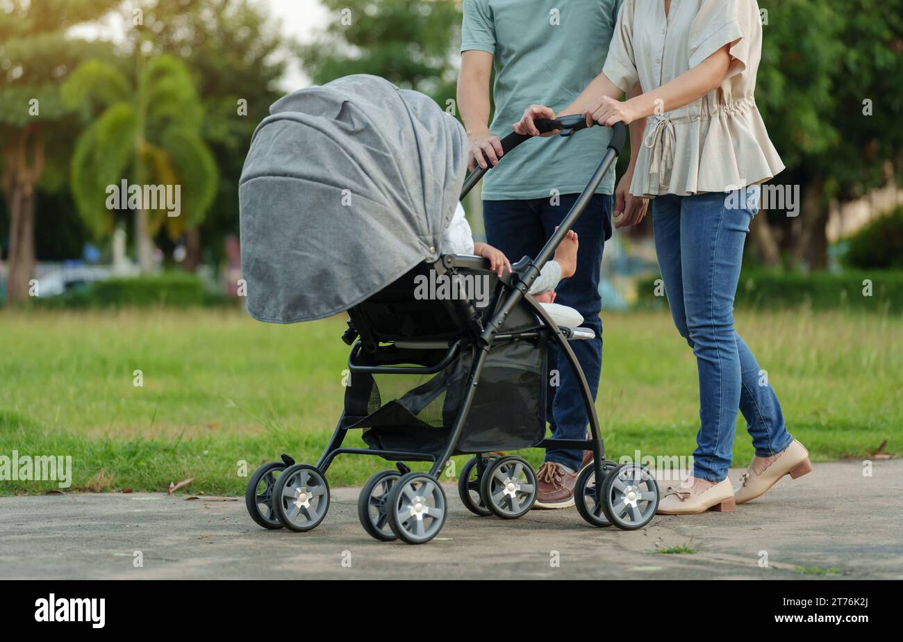 parent (father and mother) pushing infant baby stroller and walking in ...