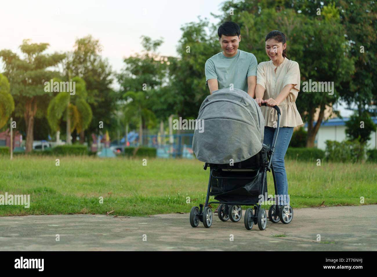 happy parent (father and mother) talking and pushing infant baby ...