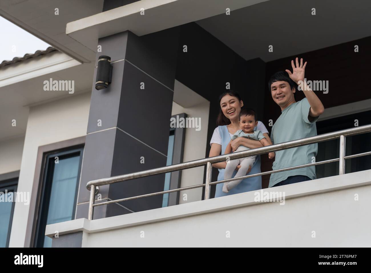 happy family (father, mother and infant baby) greeting neighbors at ...