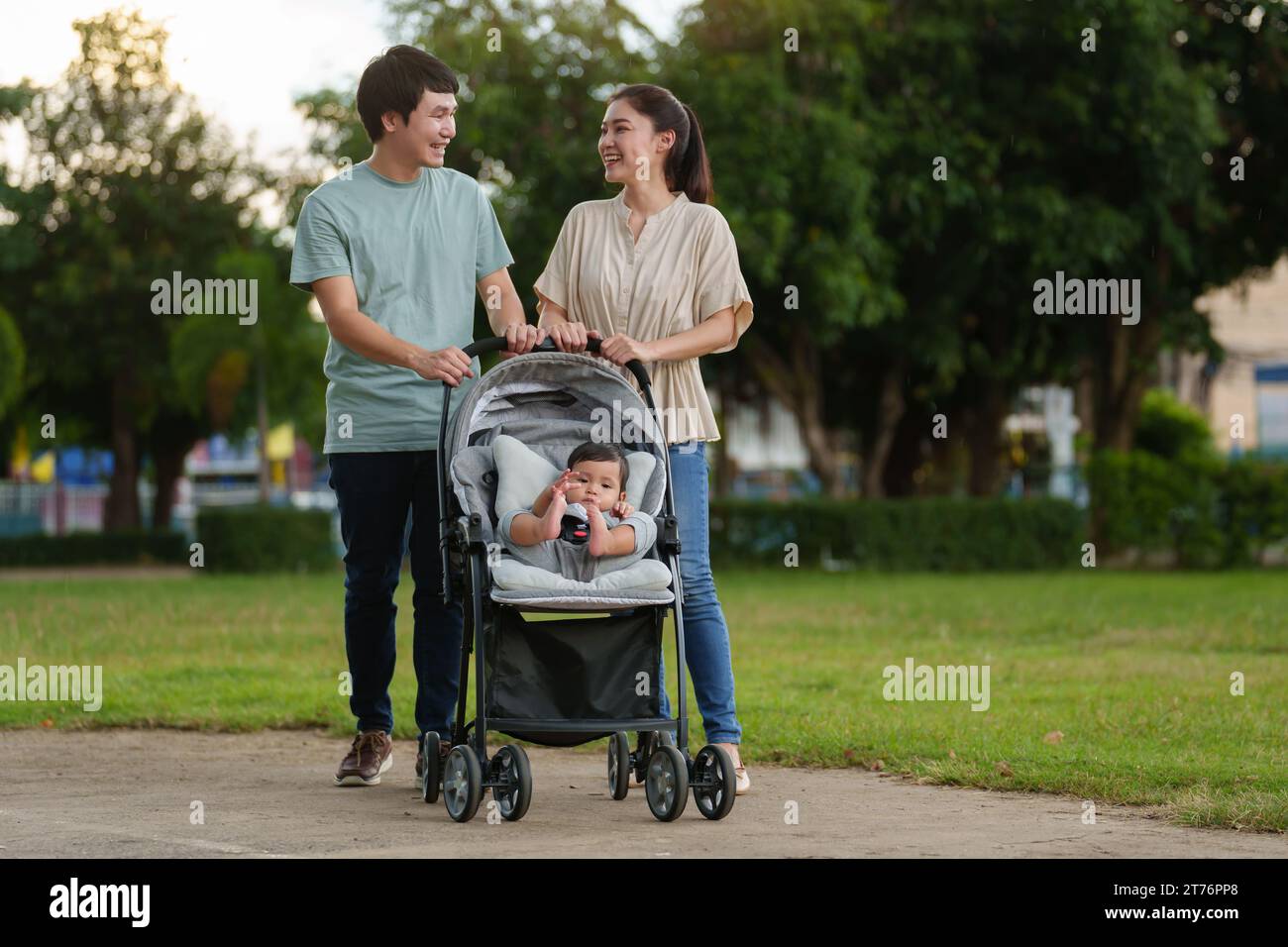 happy parent (father and mother) talking and pushing infant baby ...