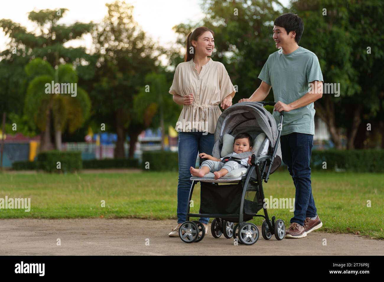 happy parent (father and mother) talking and pushing infant baby ...