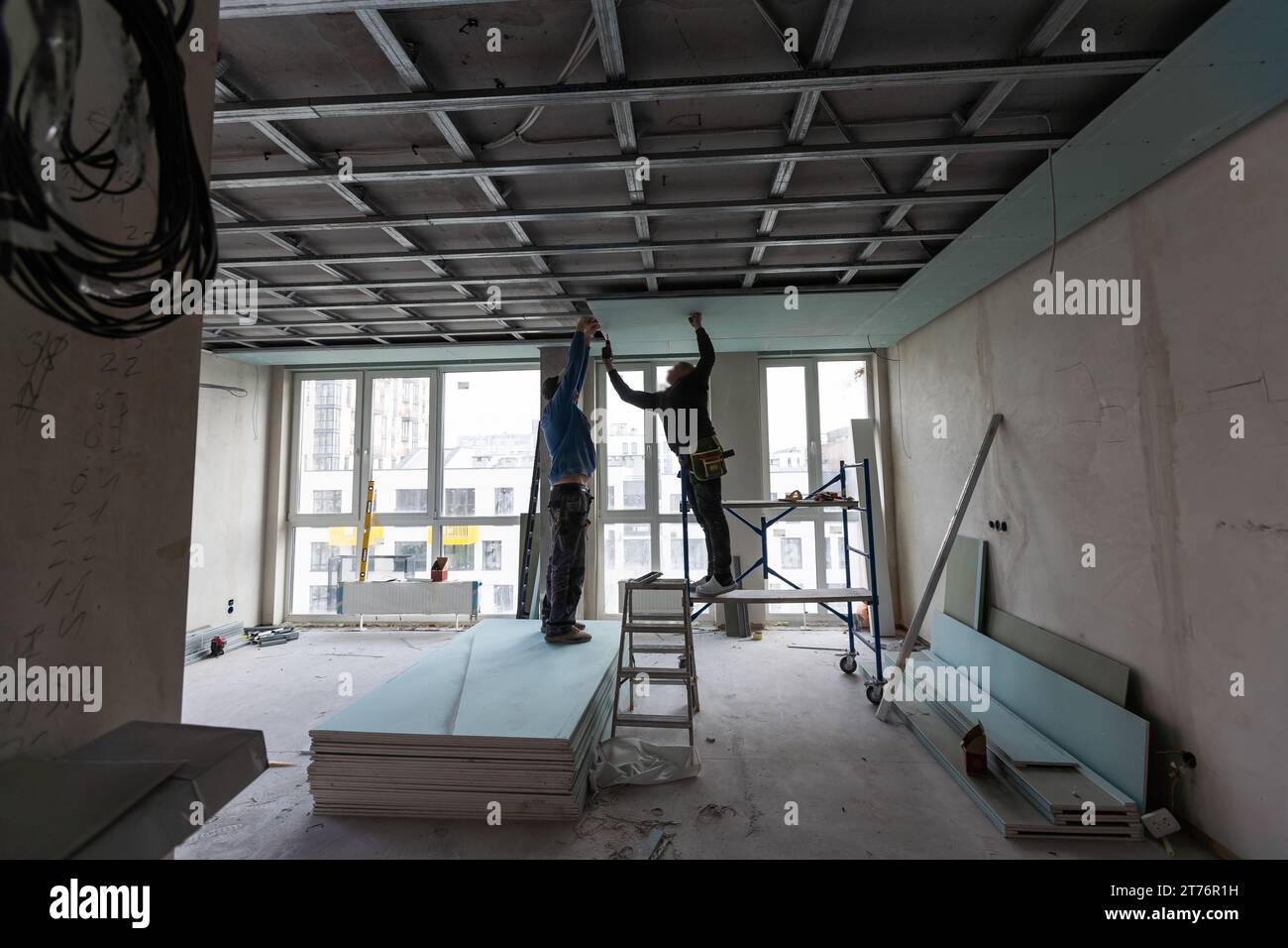 Two man help for ceiling house construction Stock Photo - Alamy