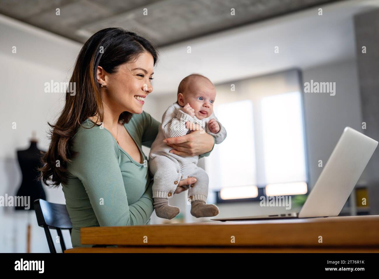 Stay at home mom working remotely on laptop while taking care of her ...