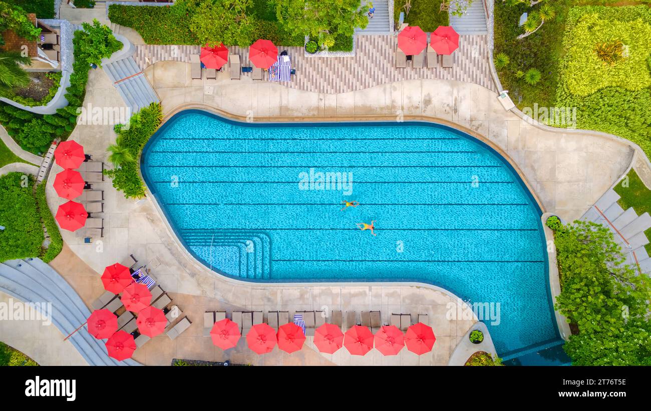 drone view from above at a couple swimming in an infinity pool on a ...