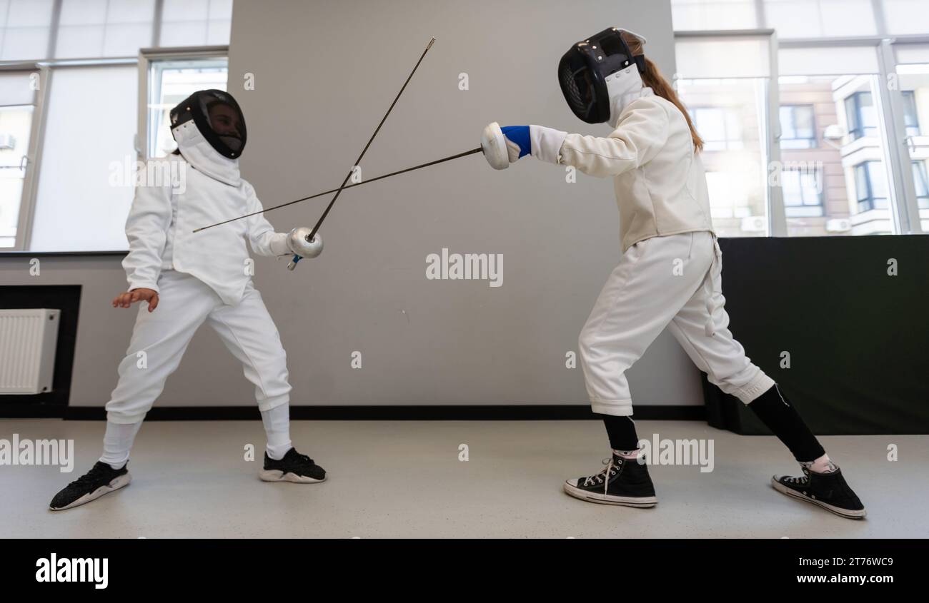 Children lunge on swords. A child in a class at a fencing school Stock ...