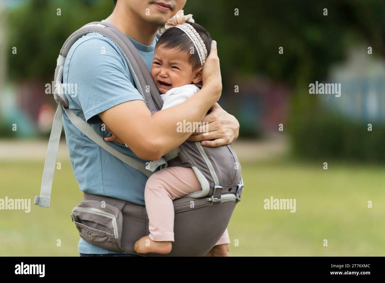 father consoling his crying infant in baby carrier in the park Stock ...