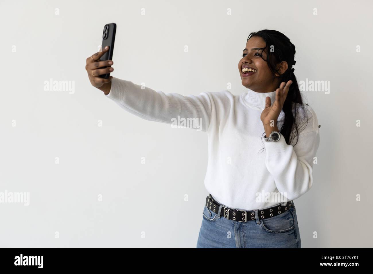 Indian woman taking selfie and doing a video call in white background ...