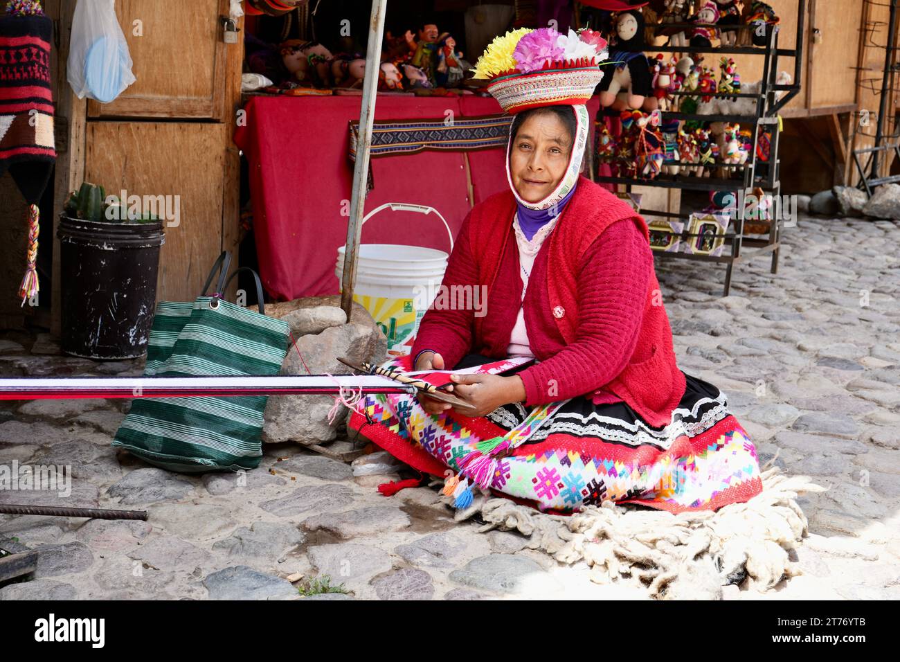 A woman in traditional peruvian clothing weaving wool at the market ...