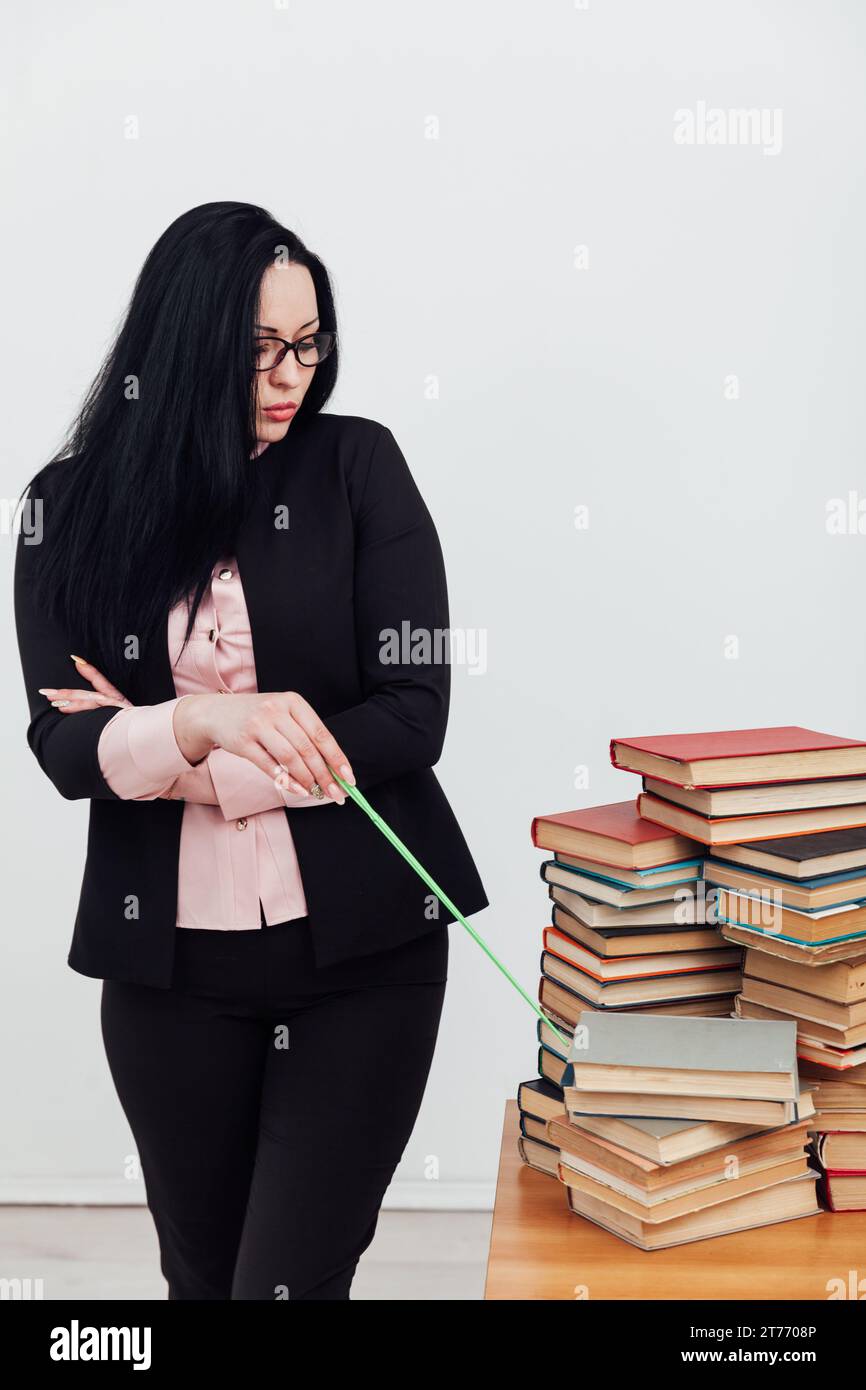 a teacher with a school pointer points to a stack of books to read ...