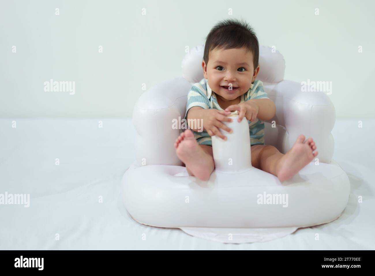 happy infant baby sitting on an inflatable chair. learning to sit Stock ...