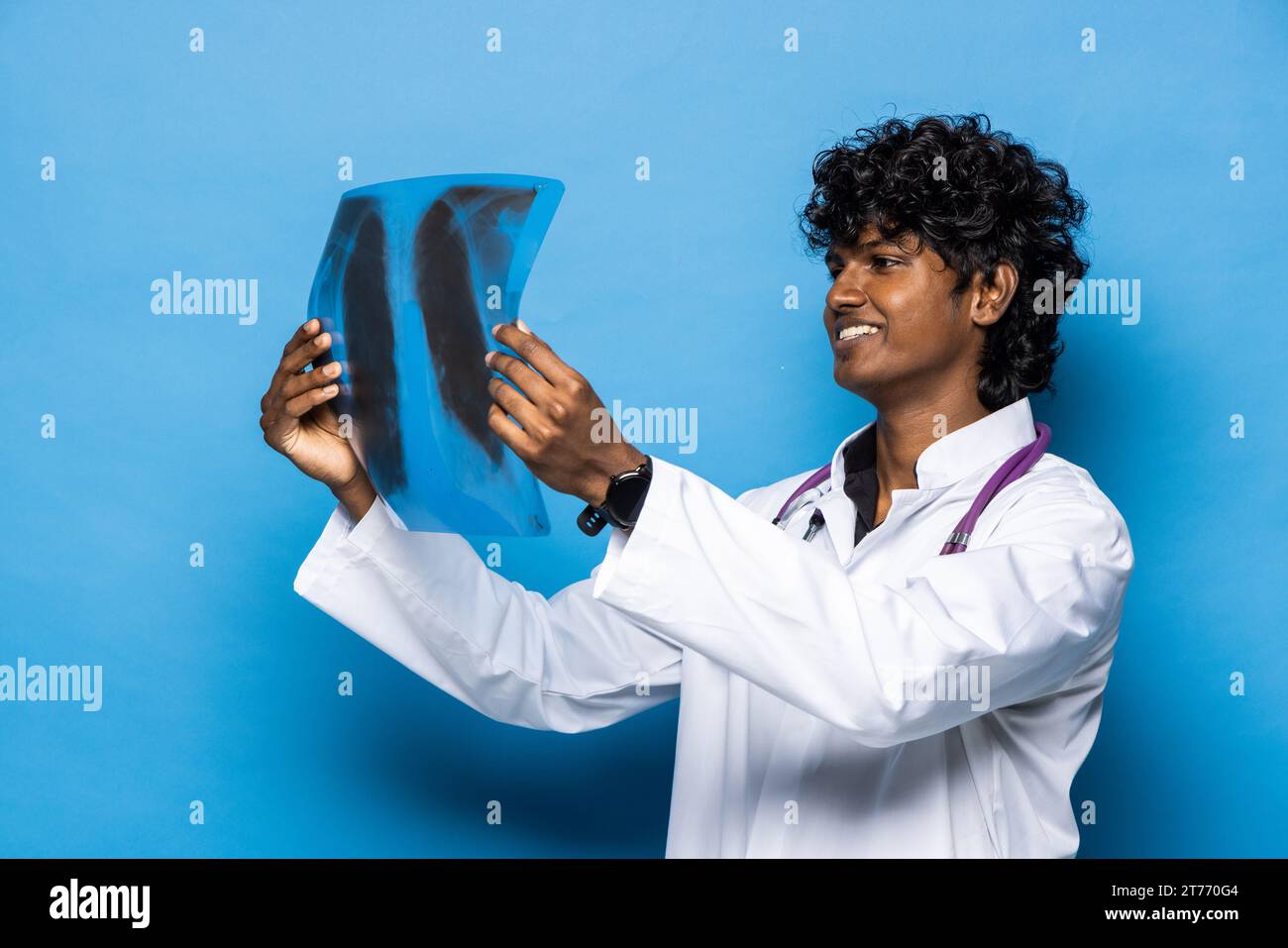 indian doctor or male nurse in blue uniform looking at x-ray scan image ...