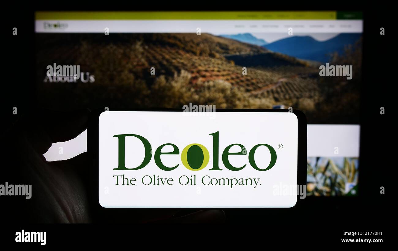 Person holding mobile phone with logo of Spanish oilve oil processing ...