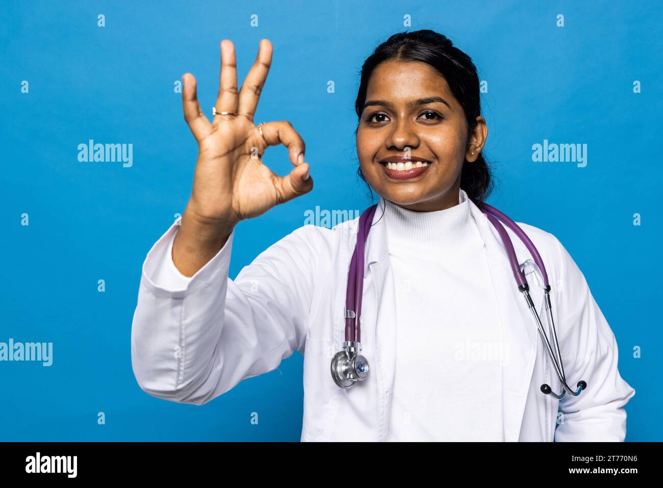 Cheerful female doctor showing OK sign isolated on white background ...