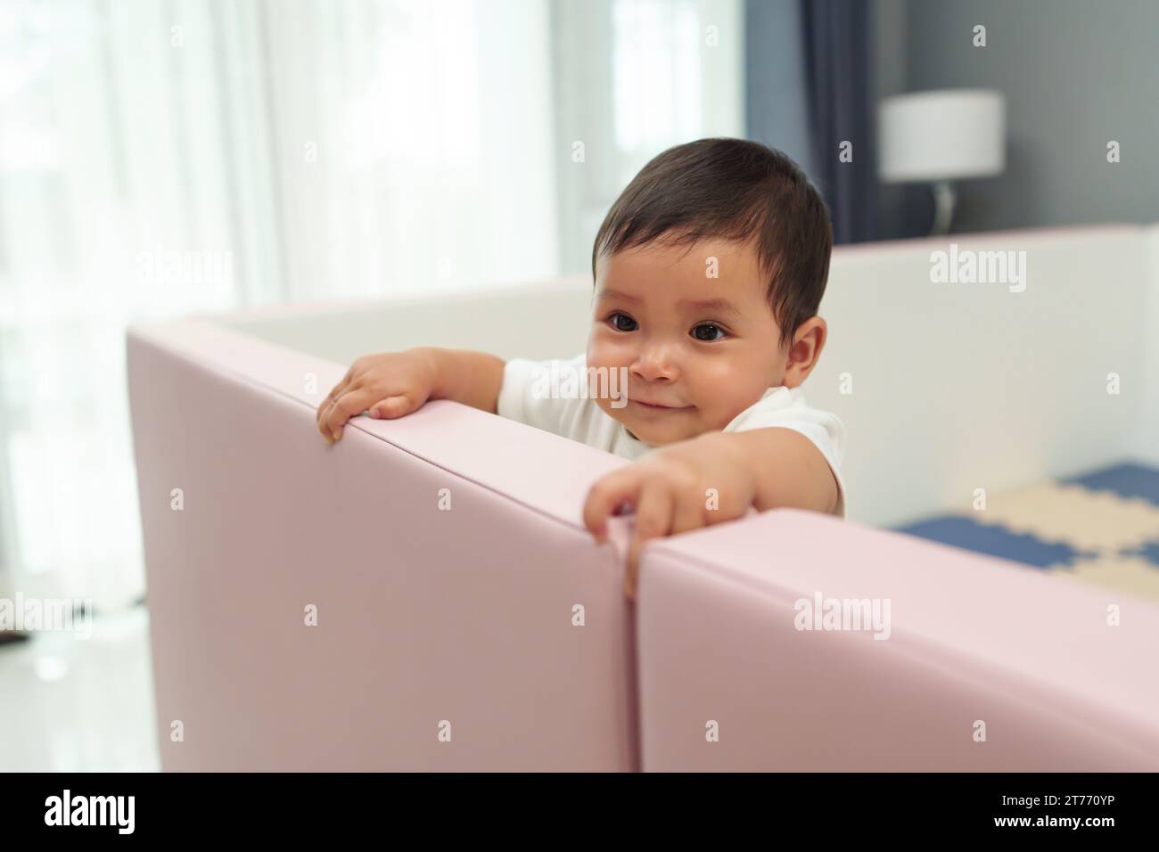 happy infant baby standing in a fence of playpen Stock Photo - Alamy