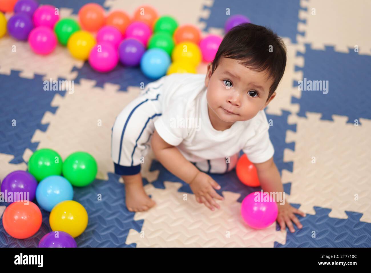 infant baby playing colorful plastic balls in playpen Stock Photo - Alamy