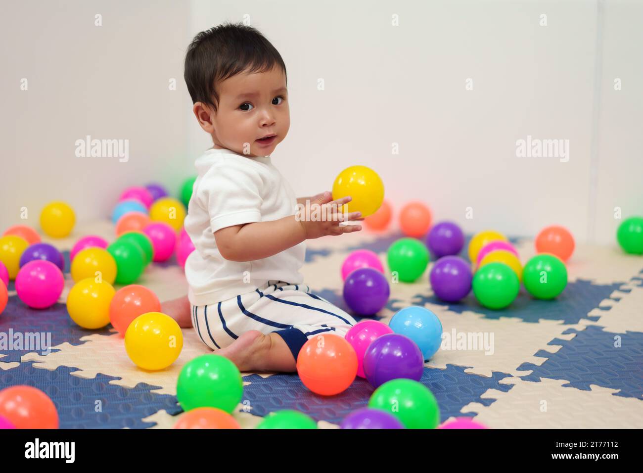 happy infant baby playing colorful plastic balls in playpen Stock Photo ...