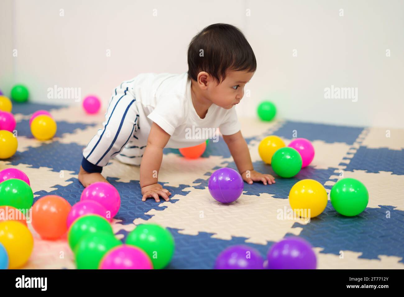 infant baby playing colorful plastic balls in playpen Stock Photo - Alamy