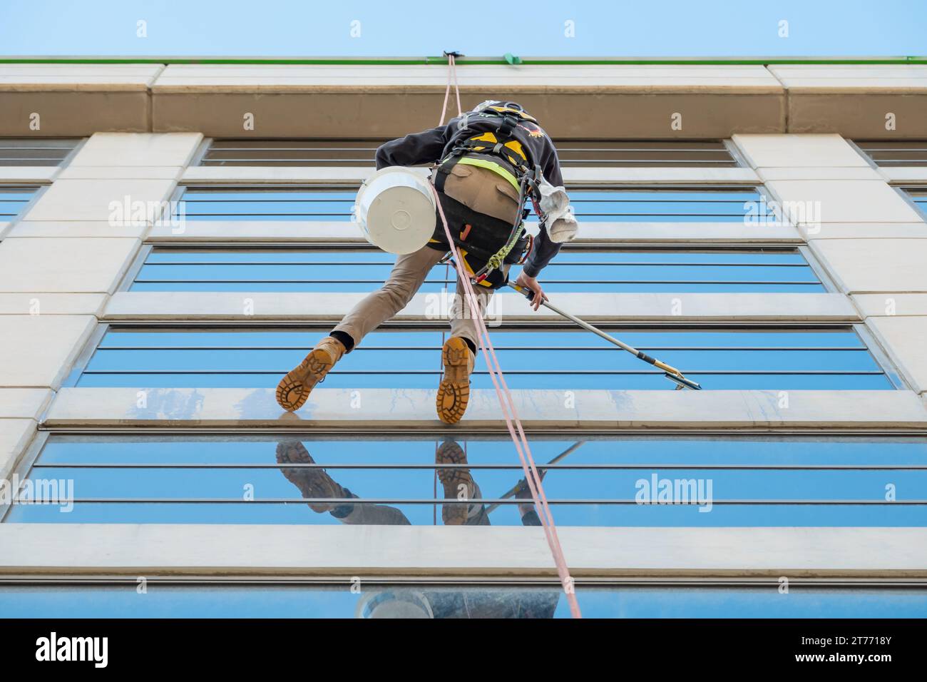 Looking up a t a window washer dangling from a rope on the side of a ...