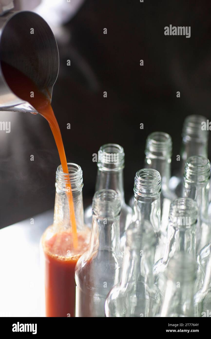 Tomato sauce being poured into a glass bottle Stock Photo - Alamy