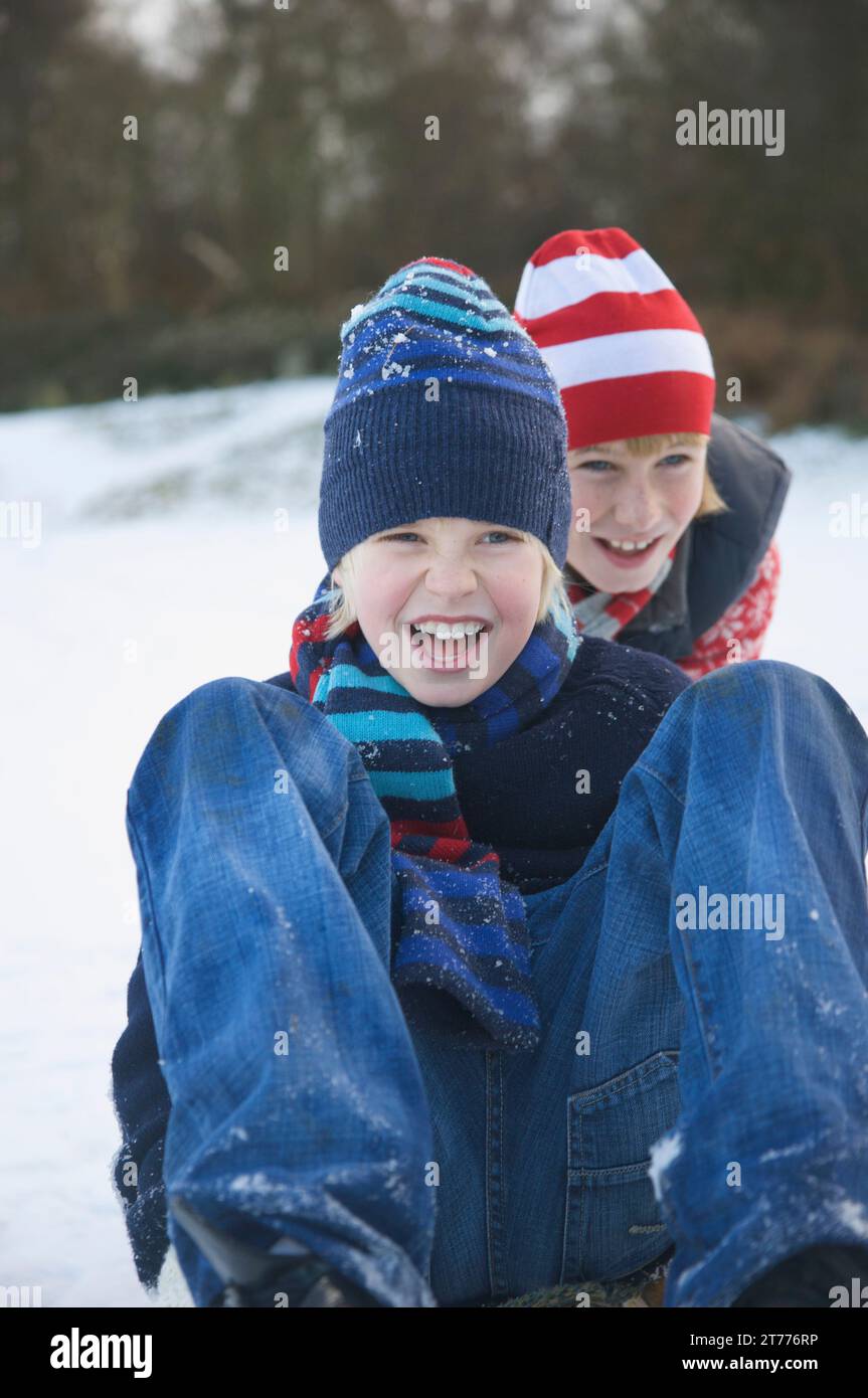 Close up of a boy pushing a friend sitting on sled Stock Photo - Alamy