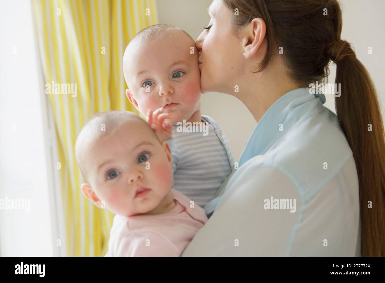 Mother Kissing Twin Babies Stock Photo - Alamy
