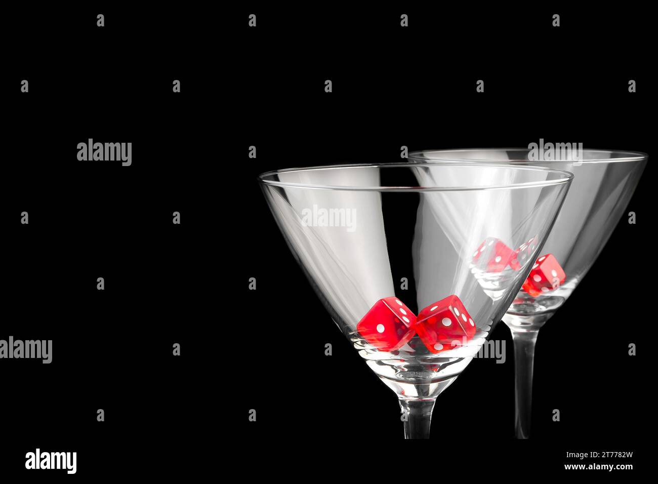 red dice in two cocktail glasses on black background with space for ...