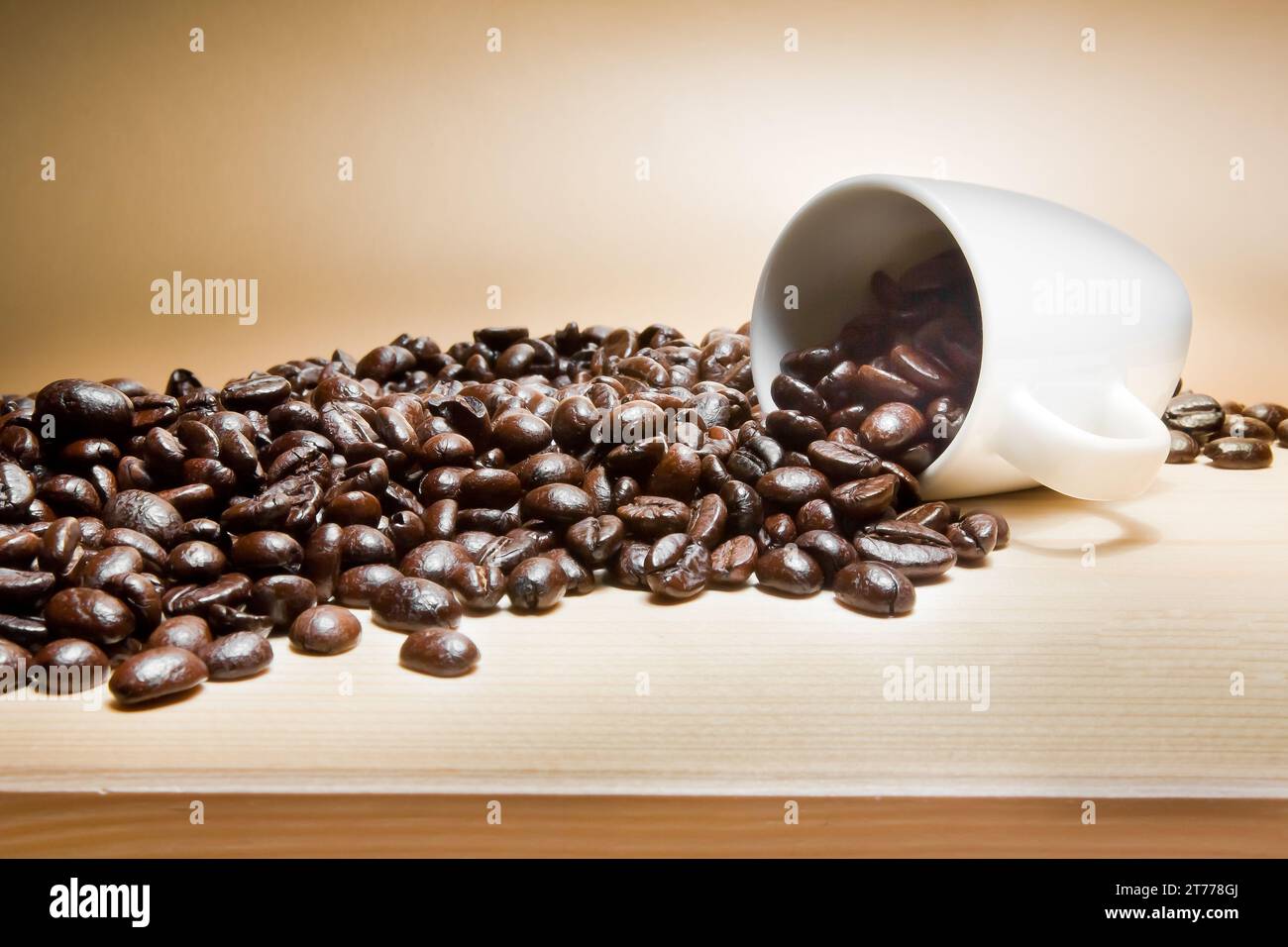 cup with coffee beans over wood table on golden background Stock Photo ...