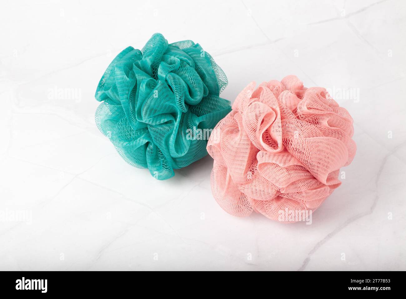 spherical polyester bath sponges on a white marble surface. Taking bath ...