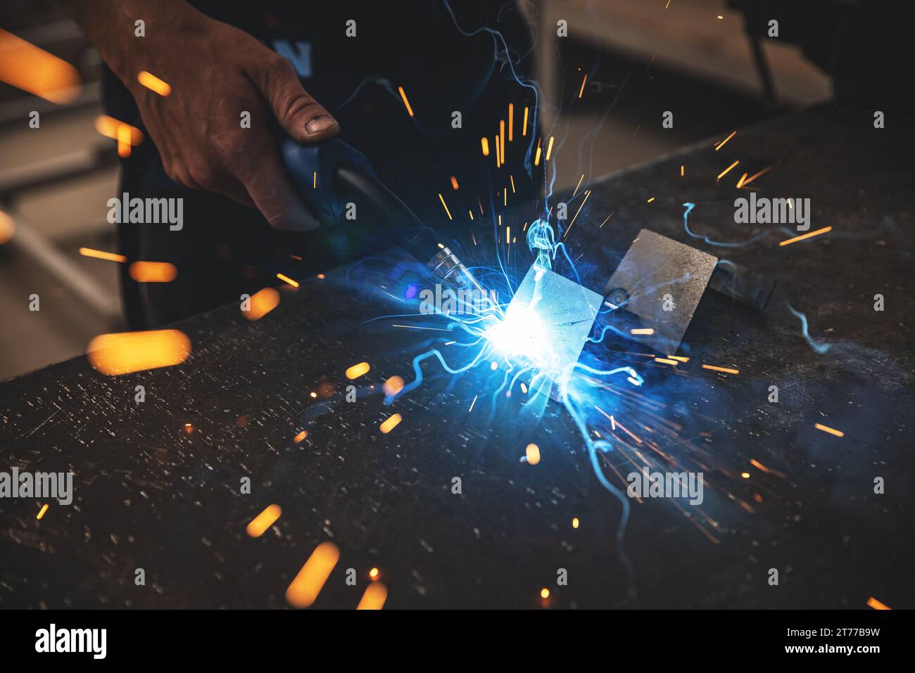 Male worker hand welding steel rack, close up. Sparks in metalworking ...