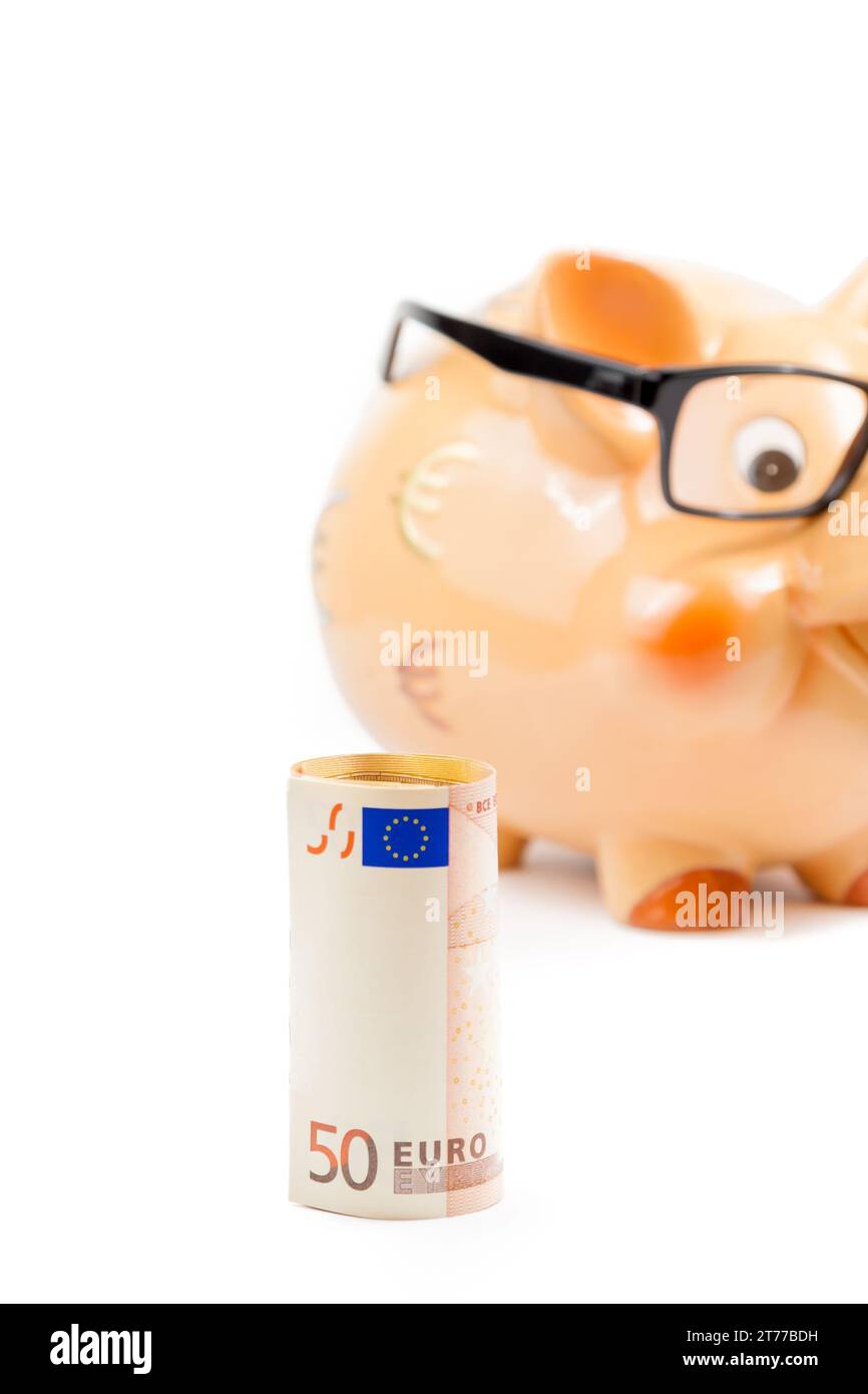 fifty euro banknote in front of unfocused piggy bank with glasses on ...