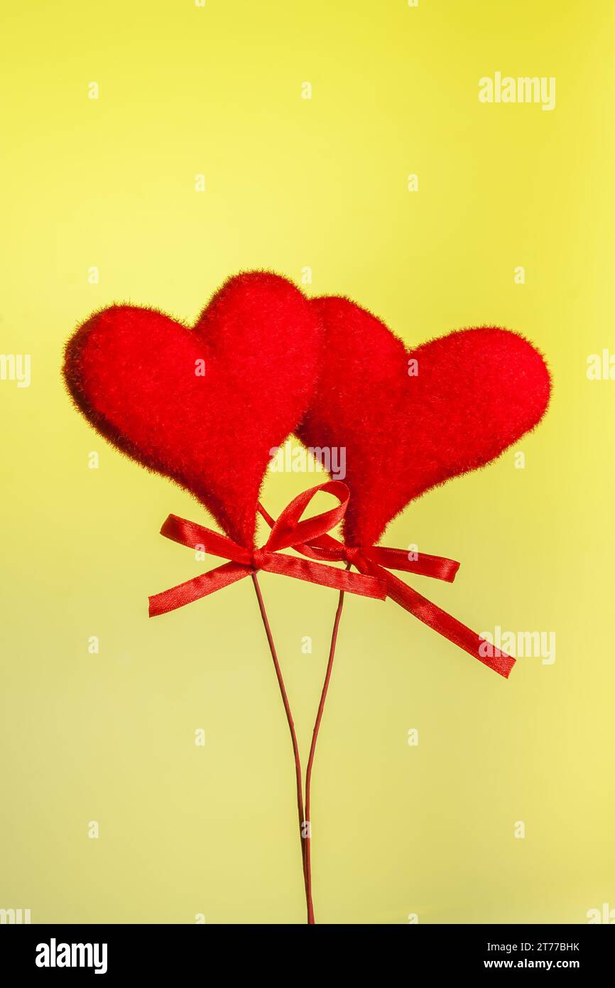 two red velvet hearts on yellow tint light background with space for ...