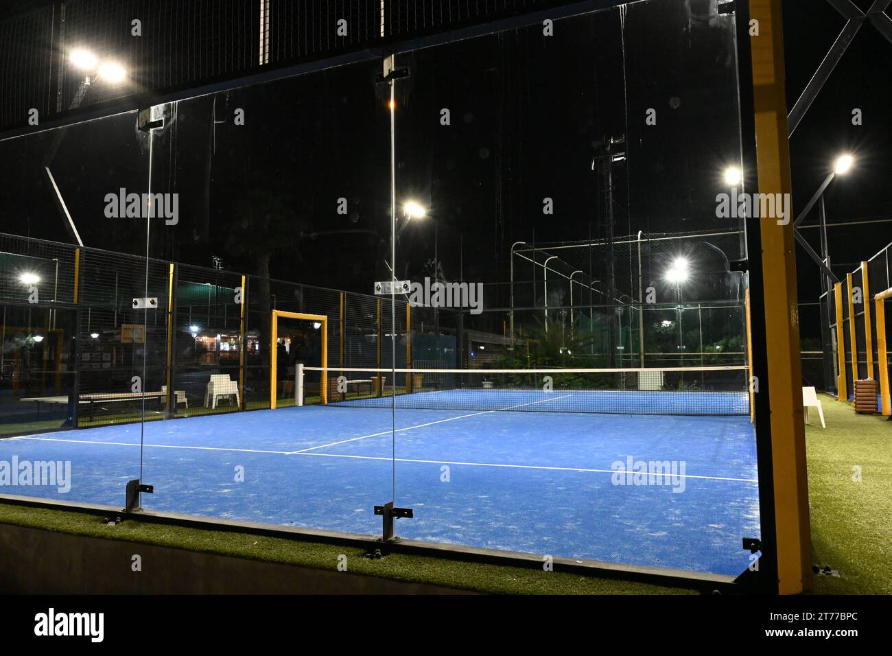 Night view on enclosed blue court for padel with construction created ...