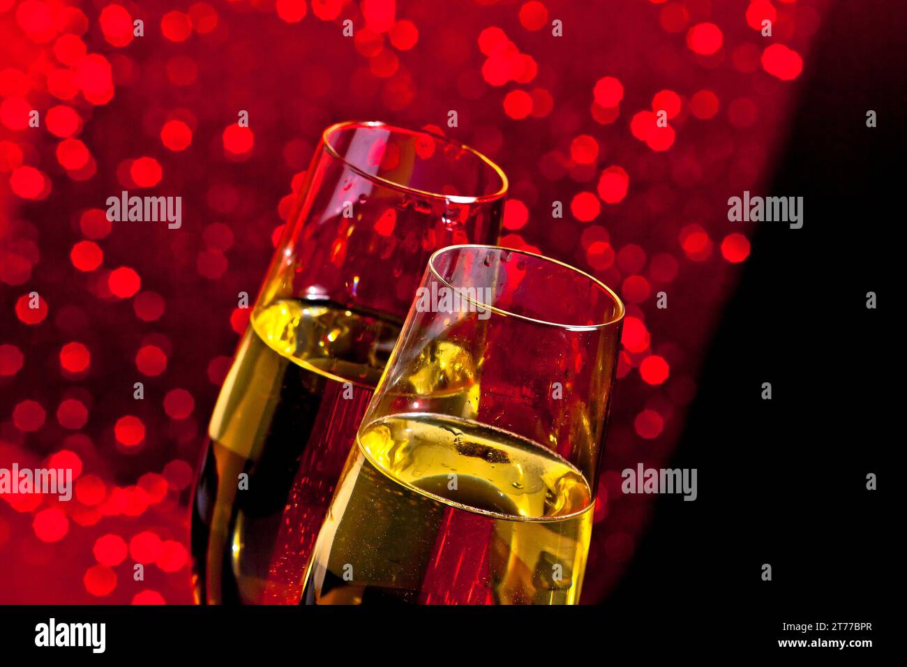 champagne flutes with golden bubbles on dark red light bokeh background ...