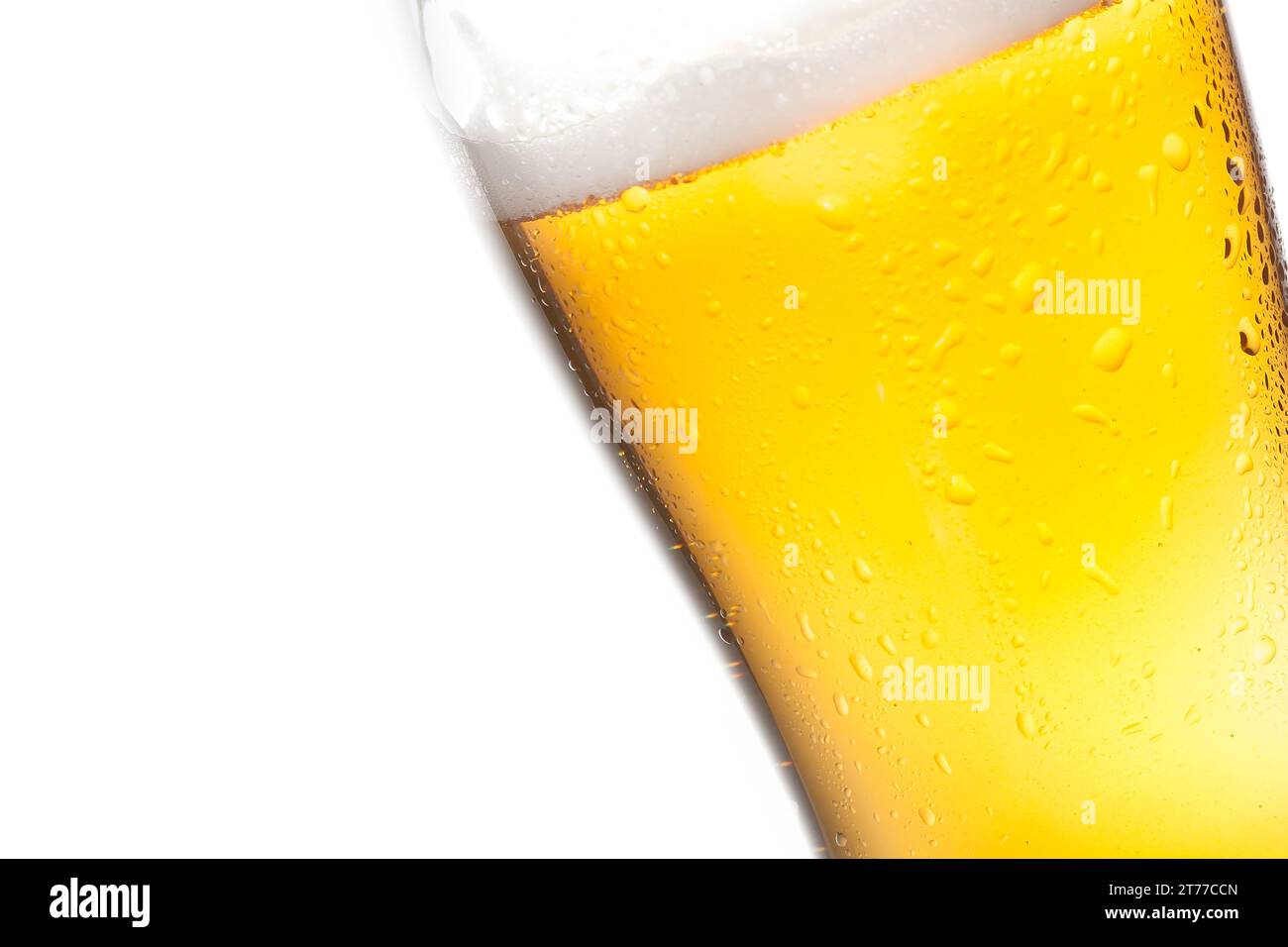 detail of tilted glass of fresh beer with drops on white background ...