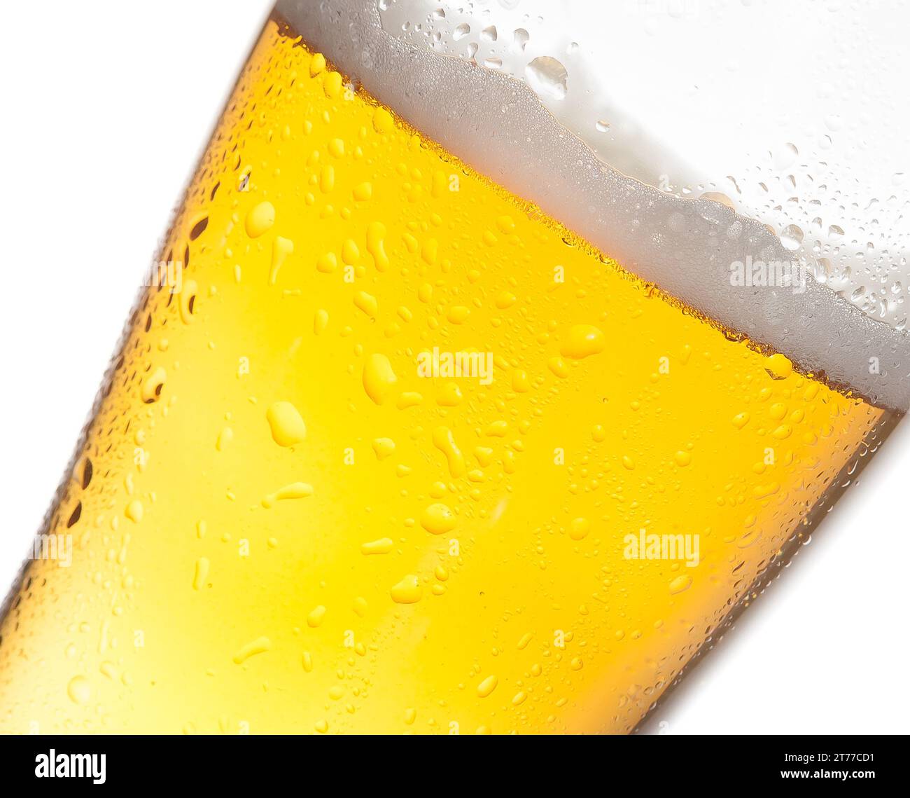 detail of tilted glass of fresh beer with drops on white background ...