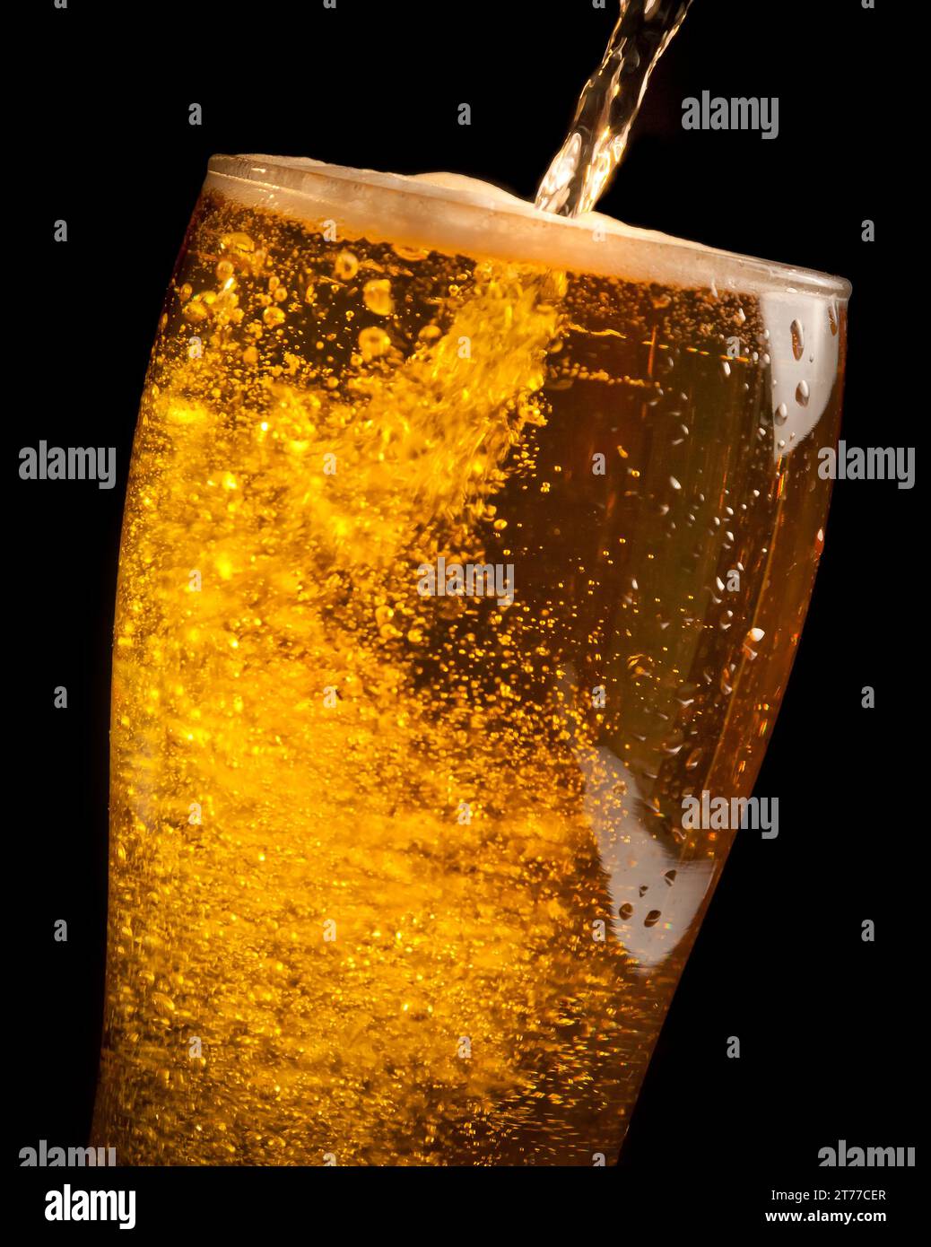 detail of fresh beer pouring from bottle into glass on black background ...