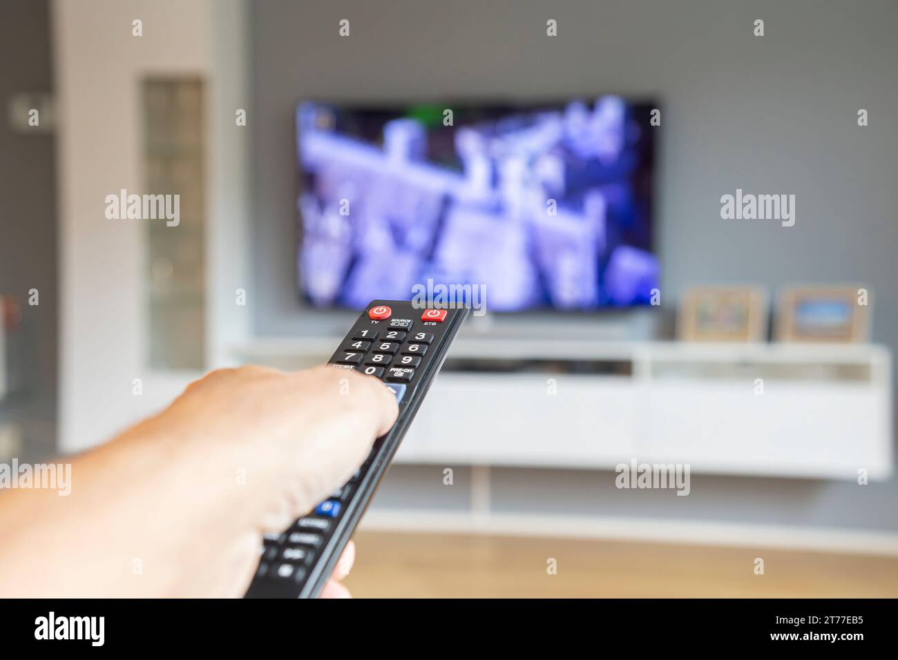 male hand holding tv remote control and watching tv in living room at ...