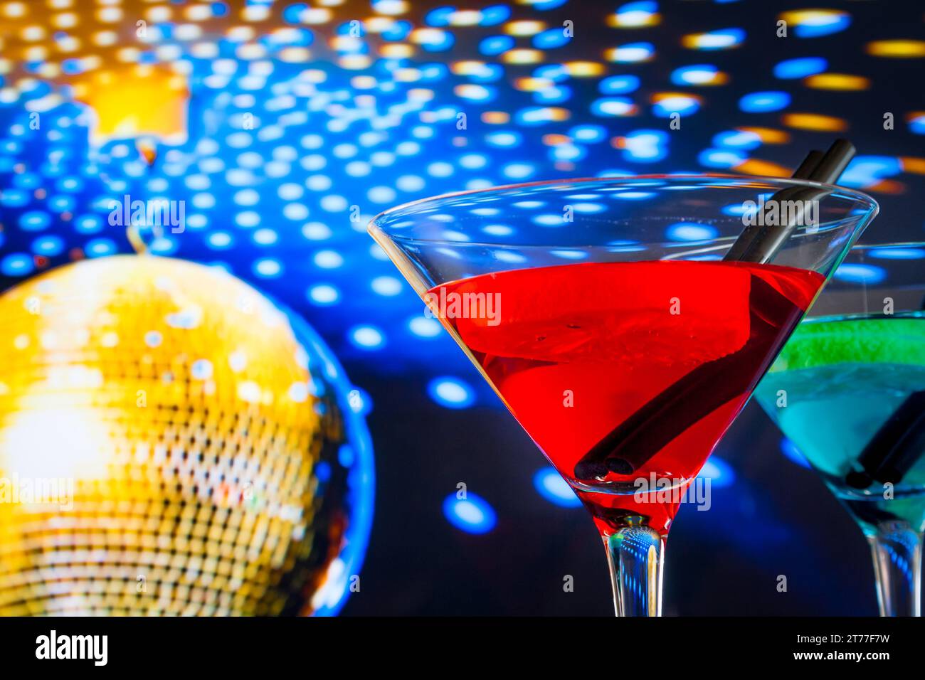 red cocktail with golden sparkling disco ball background with space for ...