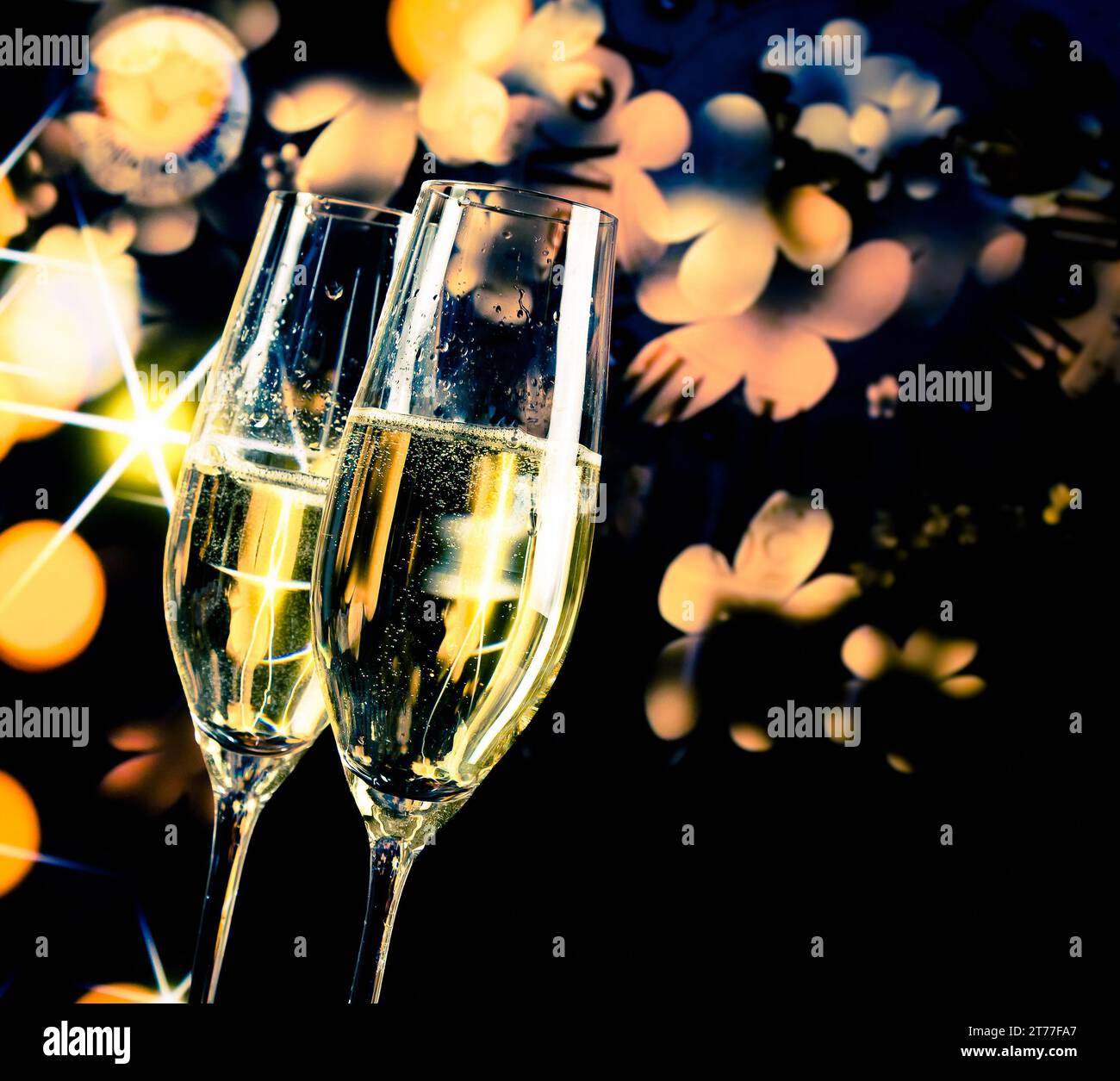 a pair of champagne flutes with golden bubbles on golden and dark light ...