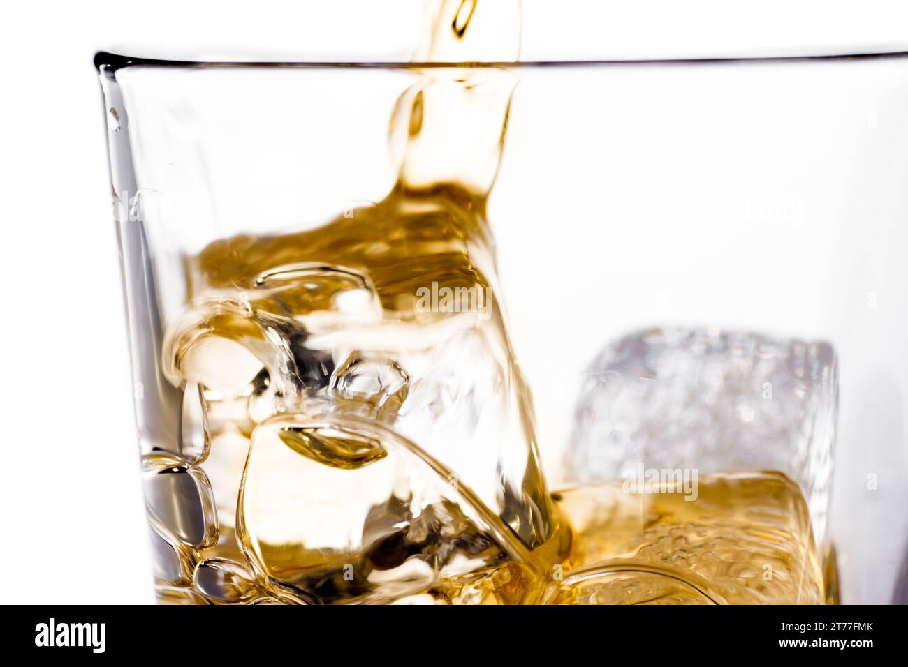 beginning pouring scotch whiskey in glass with ice cubes isolated on ...
