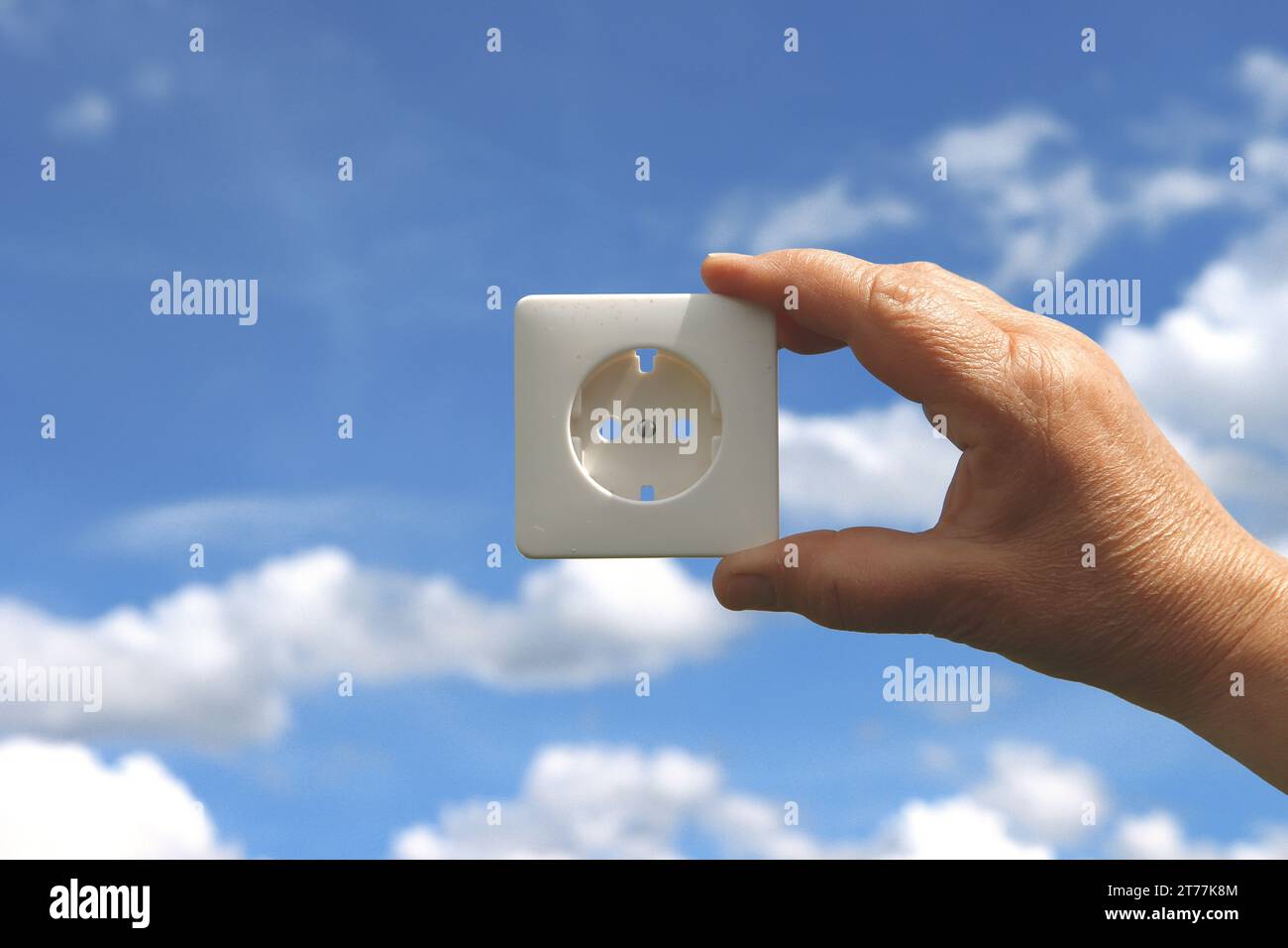 wall socket in a hand in front of blue cloudy sky Stock Photo - Alamy