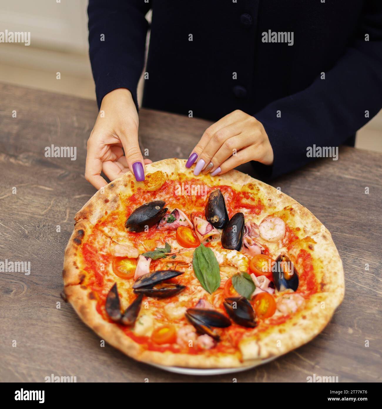 hand take pizza with sea fruit on the old table Stock Photo - Alamy