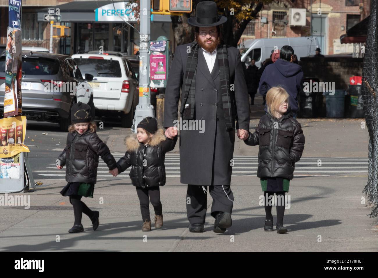 A Hasidic jewish father walks hand in hand with his son and 2 daughters ...